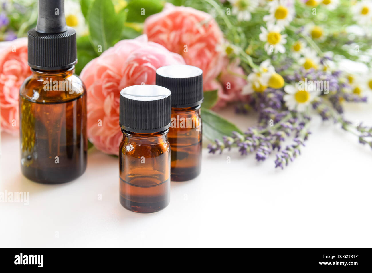 essential oils with herbal flowers and roses Stock Photo - Alamy