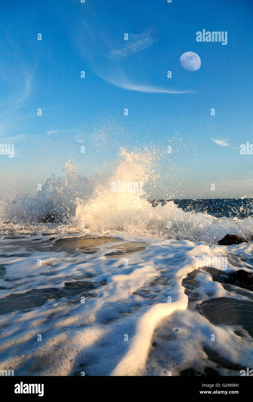 Wave splash on the rock with moon in the sky Stock Photo - Alamy