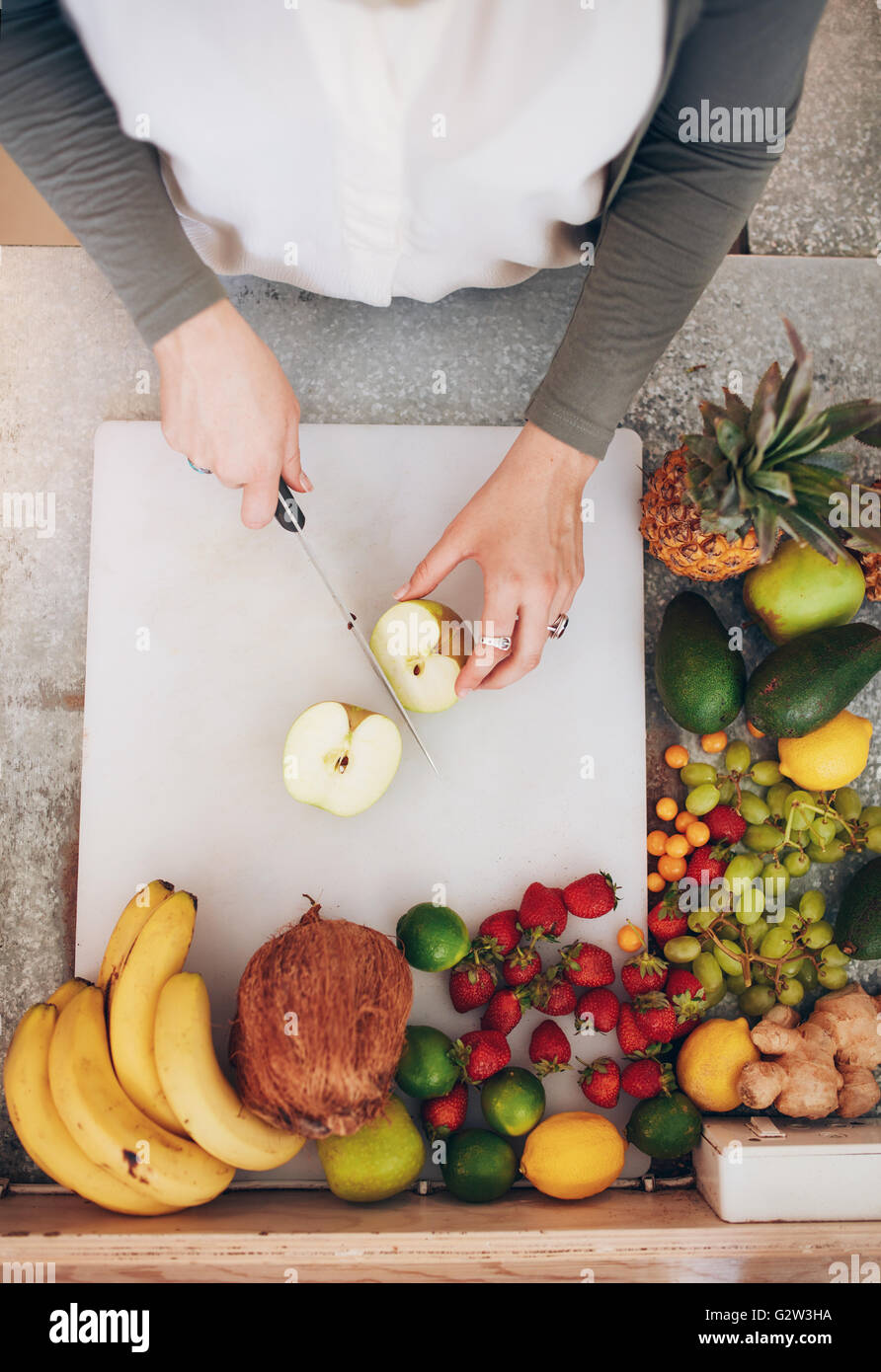 Top view of female employee working at juice bar cutting an apple ...