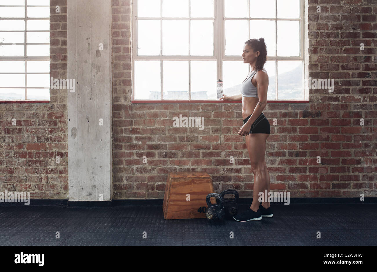 Full length shot of young female standing at gym and looking away ...