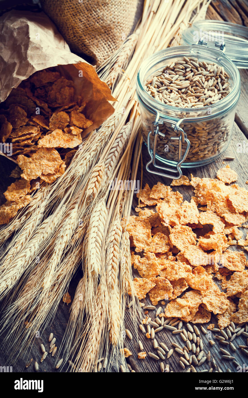 Cereal wheat flakes, spikes and rye grain on wooden table Stock Photo ...