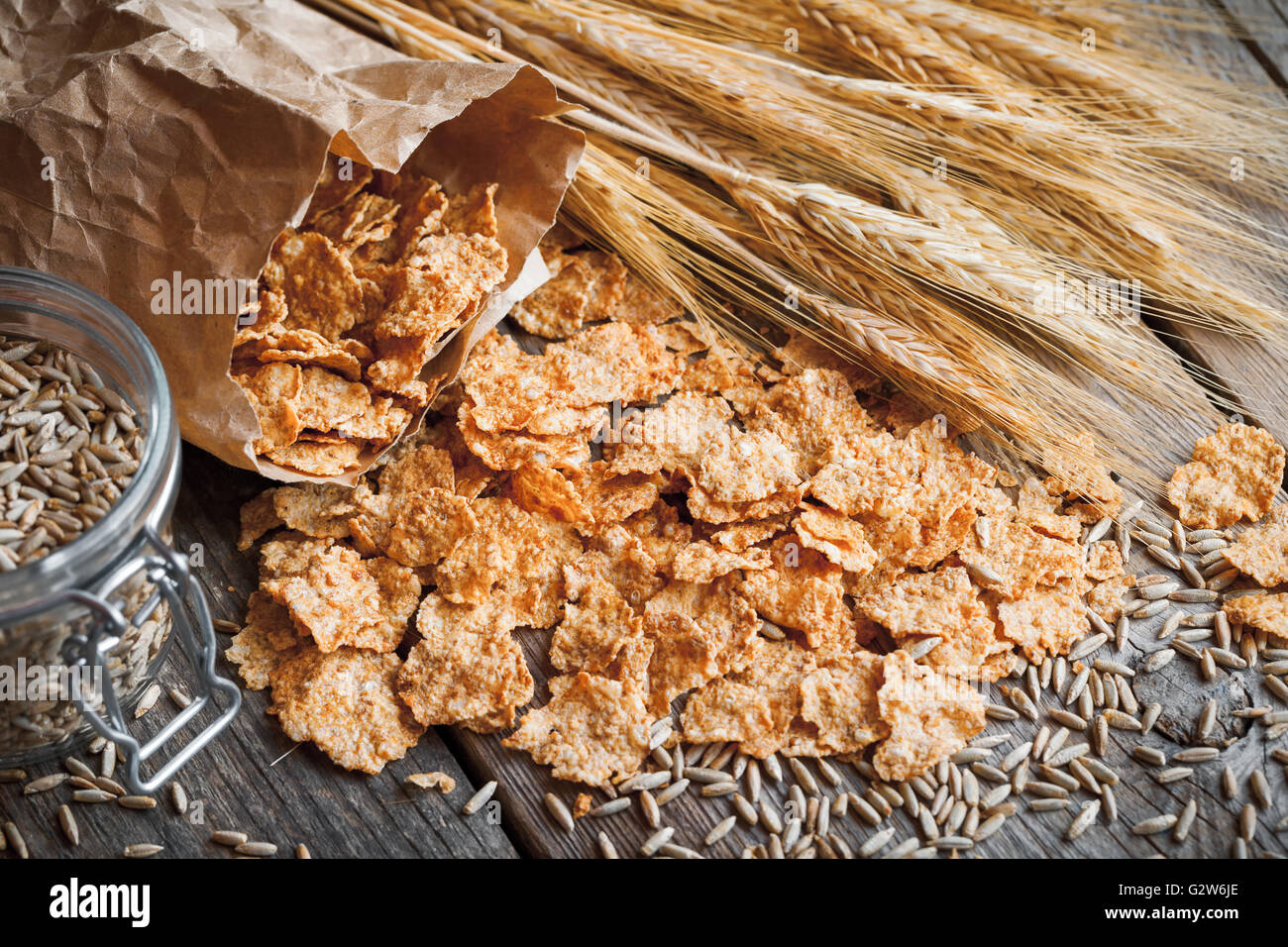 Cereal wheat flakes, spikes and rye grain on old rustic wooden table ...
