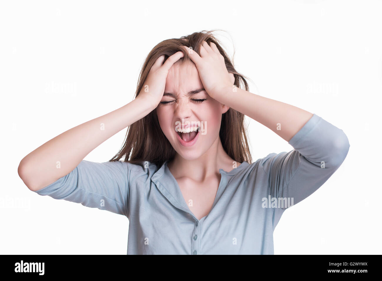 Young woman with a headache holding head and screaming Stock Photo - Alamy