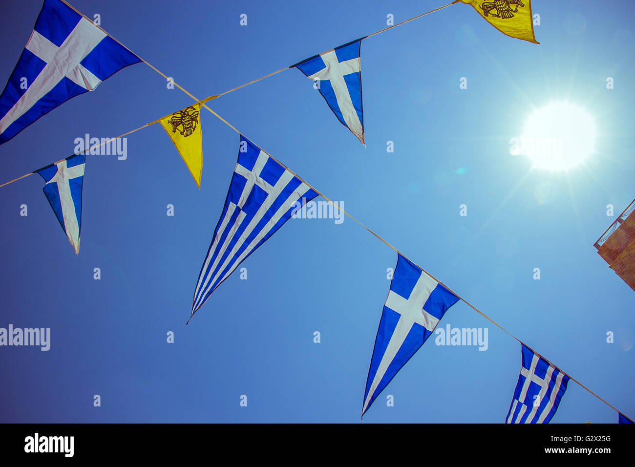 Triangular Greek sea flags on blue sky with sun as background Stock ...