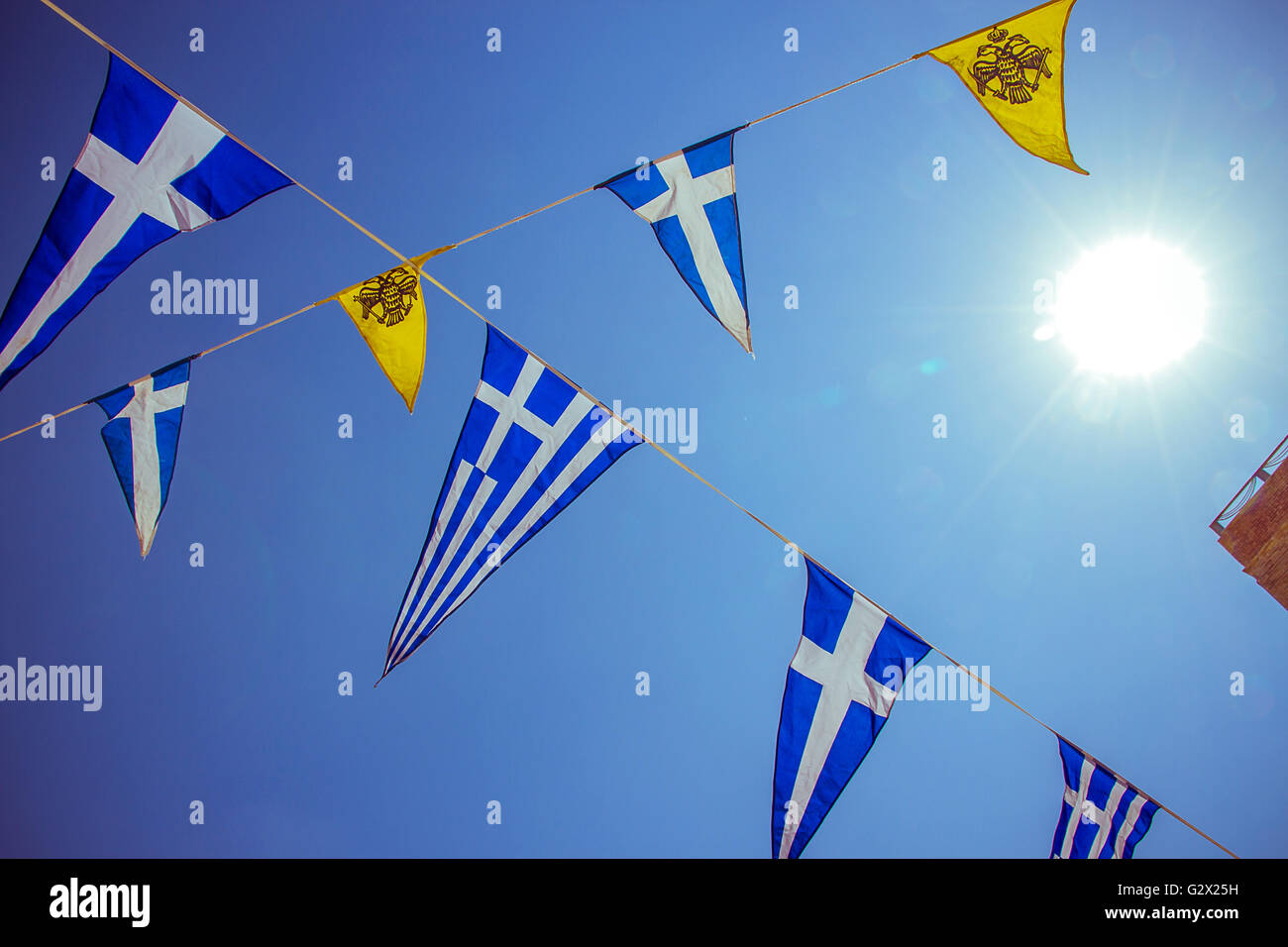 Triangular Greek sea flags on blue sky with sun as background Stock ...
