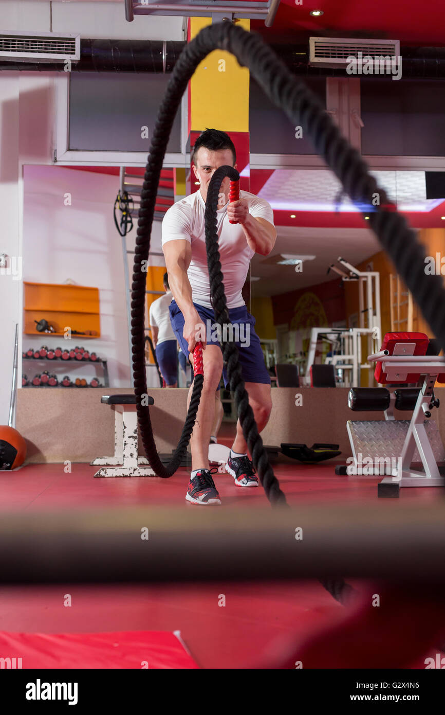 Young man working out with battle ropes at a gym Stock Photo - Alamy