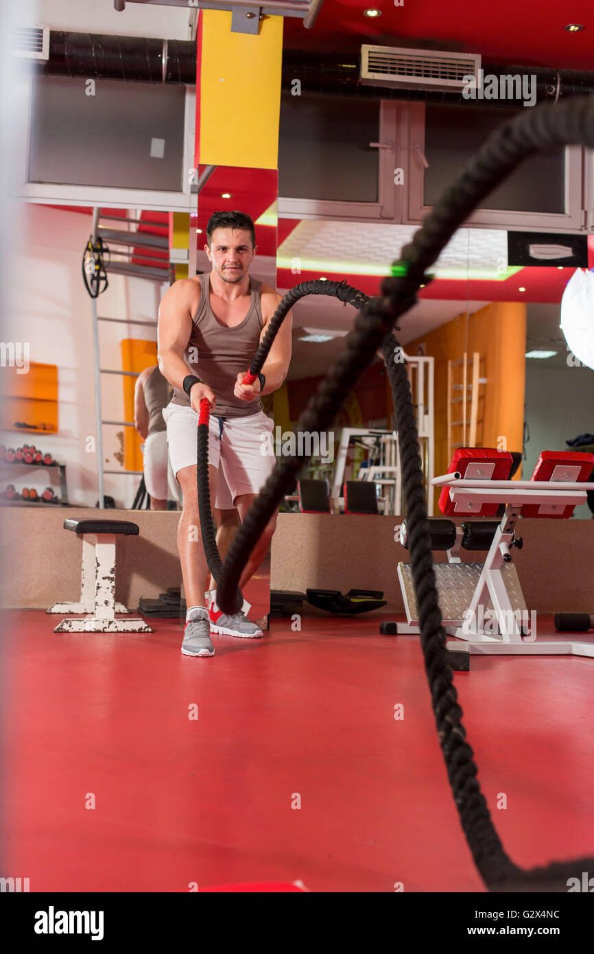 Young man working out with battle ropes at a gym Stock Photo - Alamy