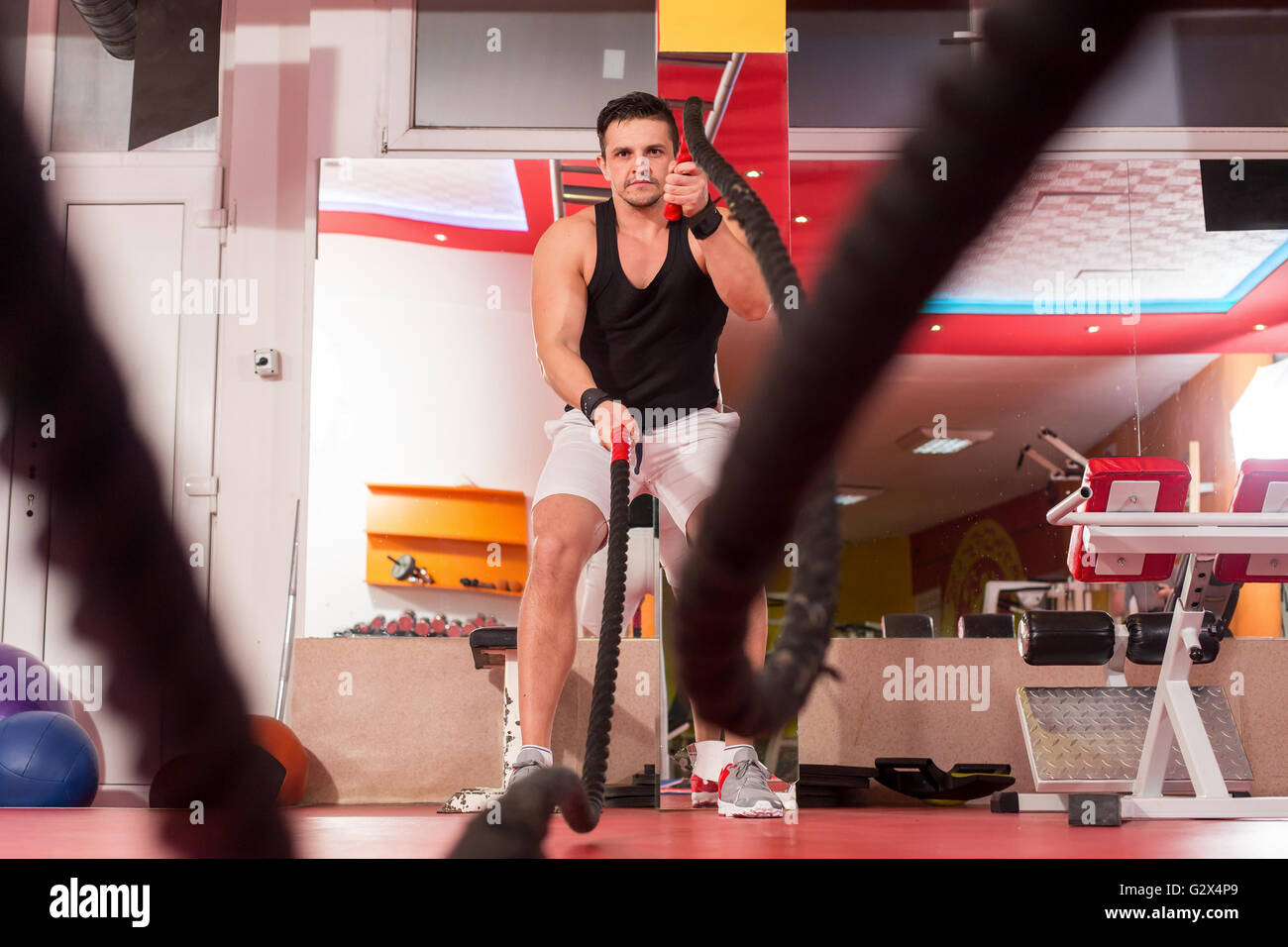 Young man working out with battle ropes at a gym Stock Photo - Alamy