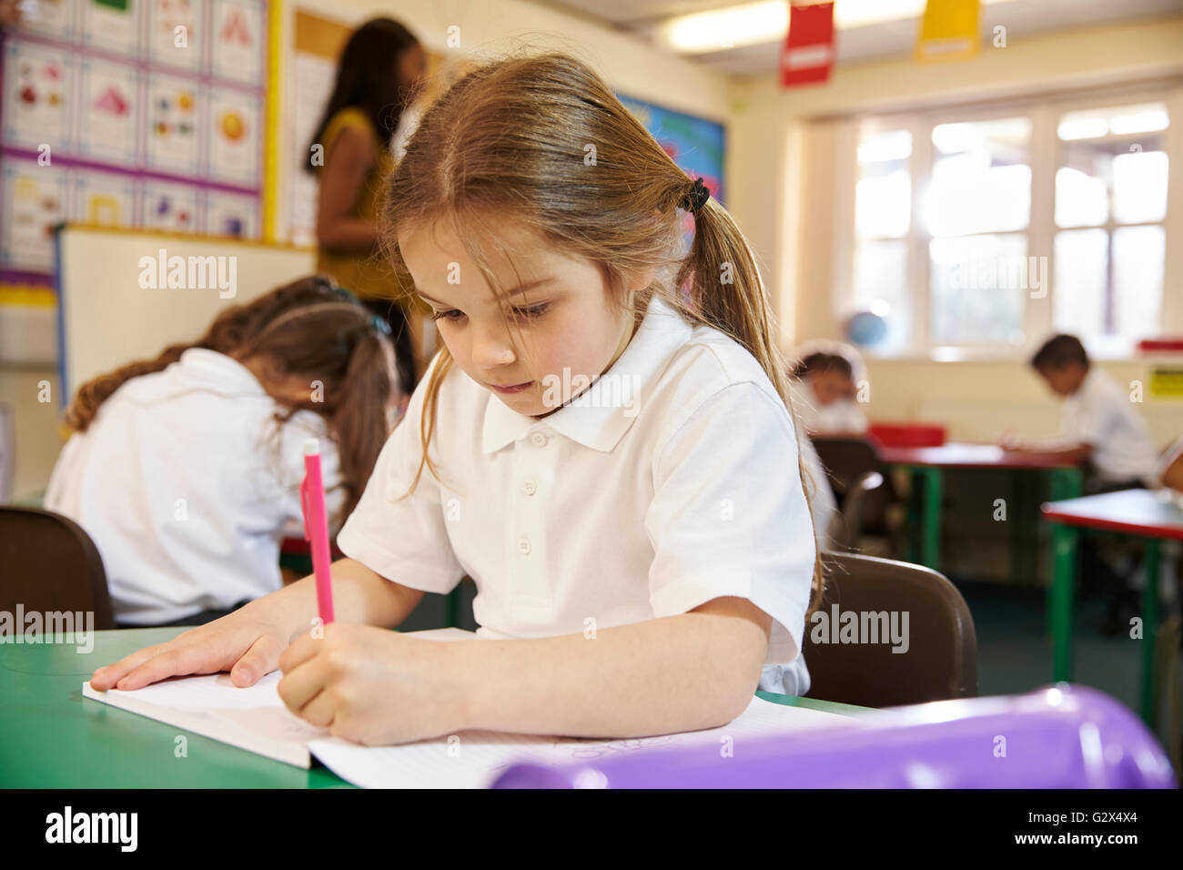Pupil Working At Desks In Elementary School Classroom Stock Photo - Alamy