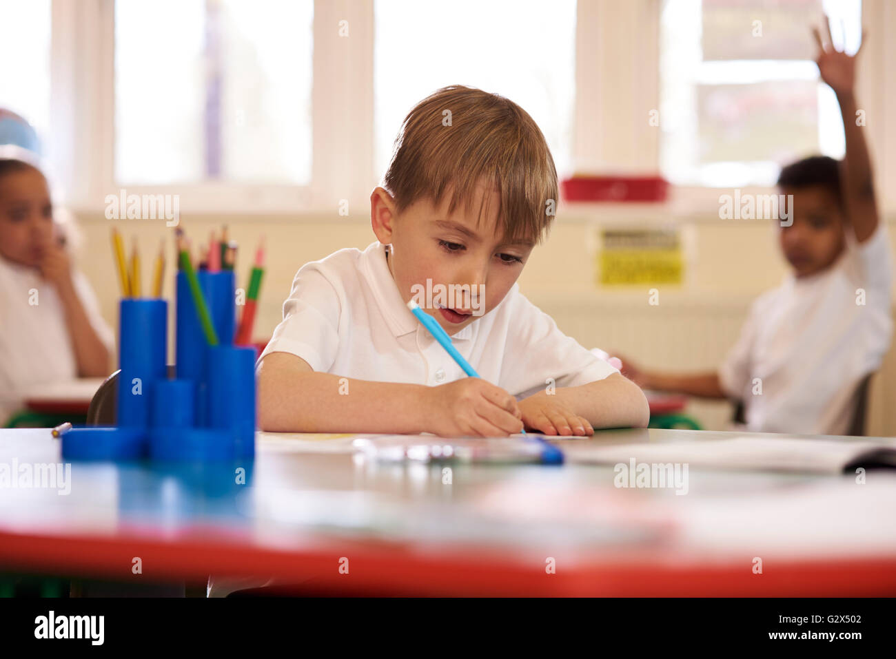 Male Pupil Working At Desk In Elementary School Classroom Stock Photo ...