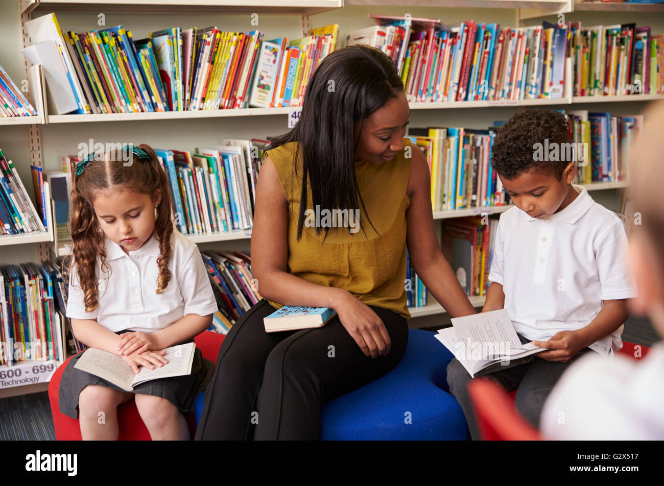 Elementary School Pupils Reading In Library With Teacher Stock Photo ...