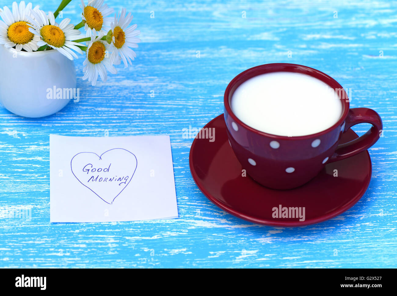 Daisy flowers and cup of milk with good morning note on rustic blue ...