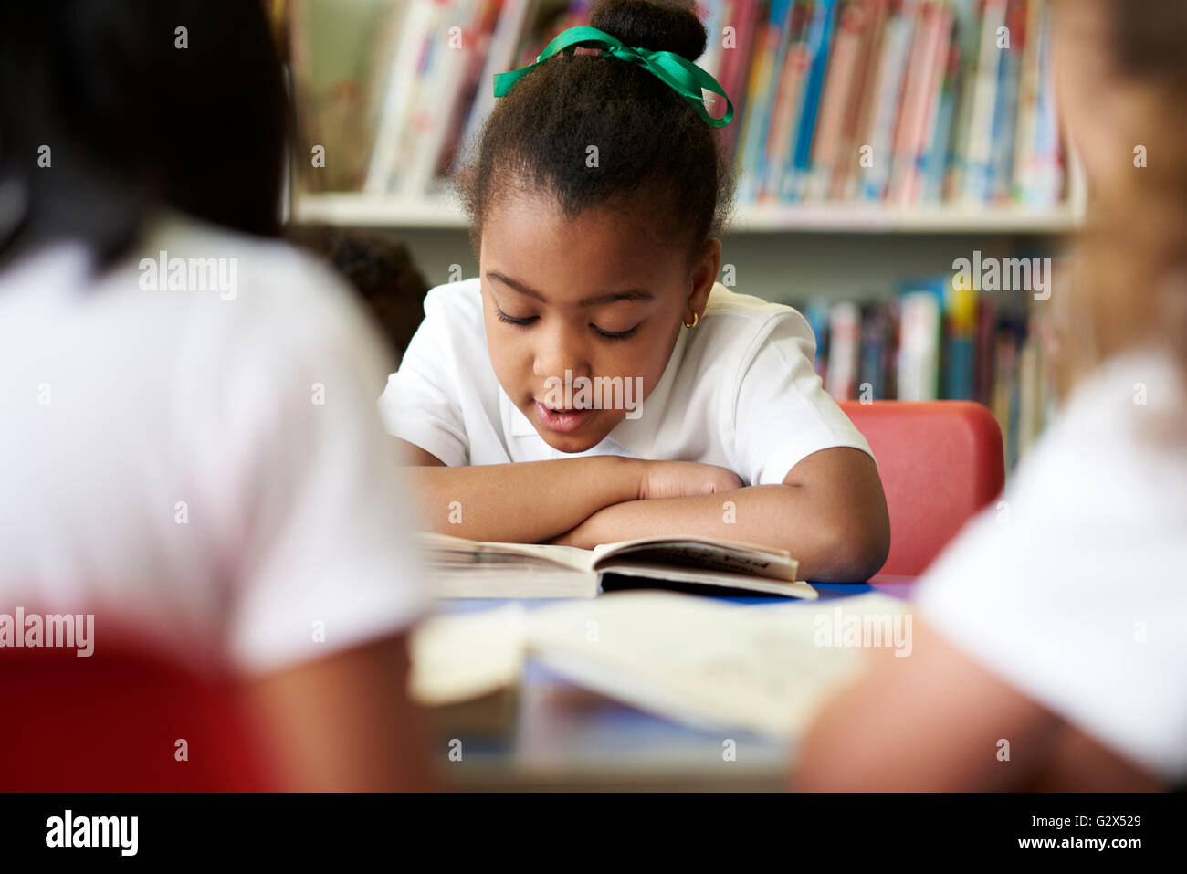 Female Elementary School Pupil Reading In Library Stock Photo - Alamy
