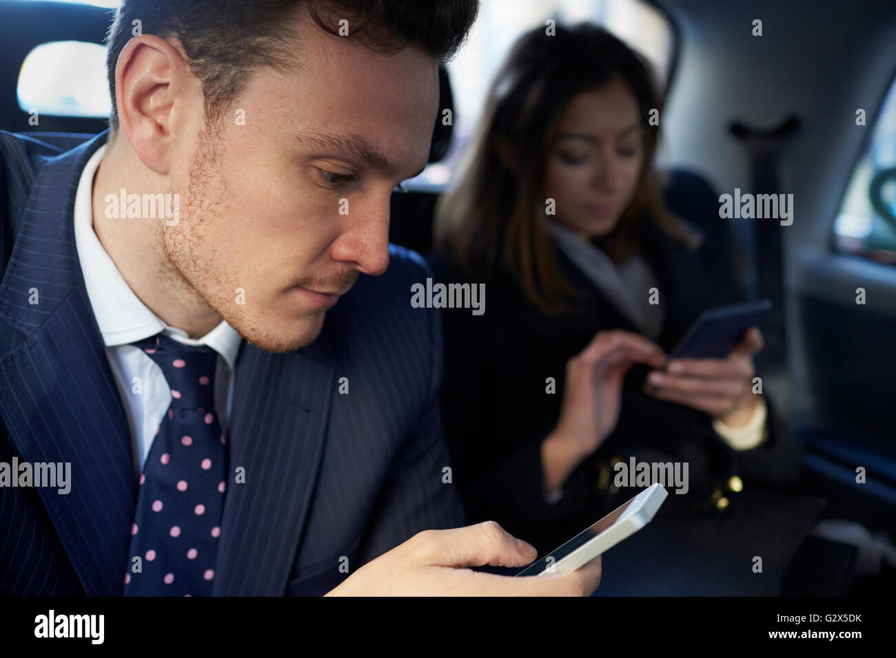 Businesspeople Travelling In Taxi Using Mobile Phones Stock Photo - Alamy