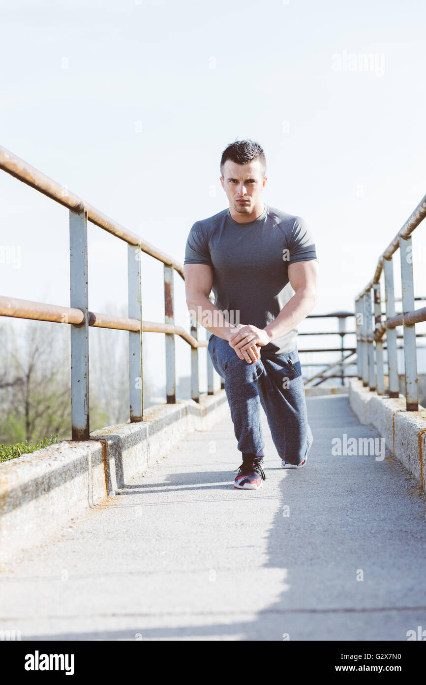 Tired after jogging. Concentrated young man resting after running while ...