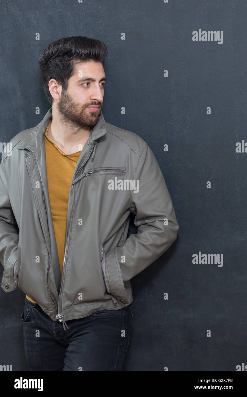 Looking cool and trendy. Handsome young bearded man posing against grey ...