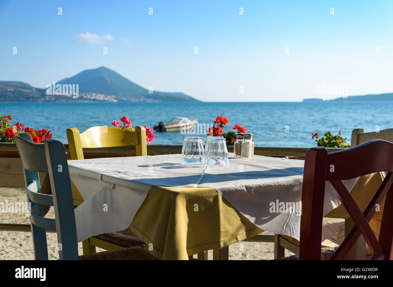 Greek tavern table with colorful wooden chairs by the sea coast. Greece ...