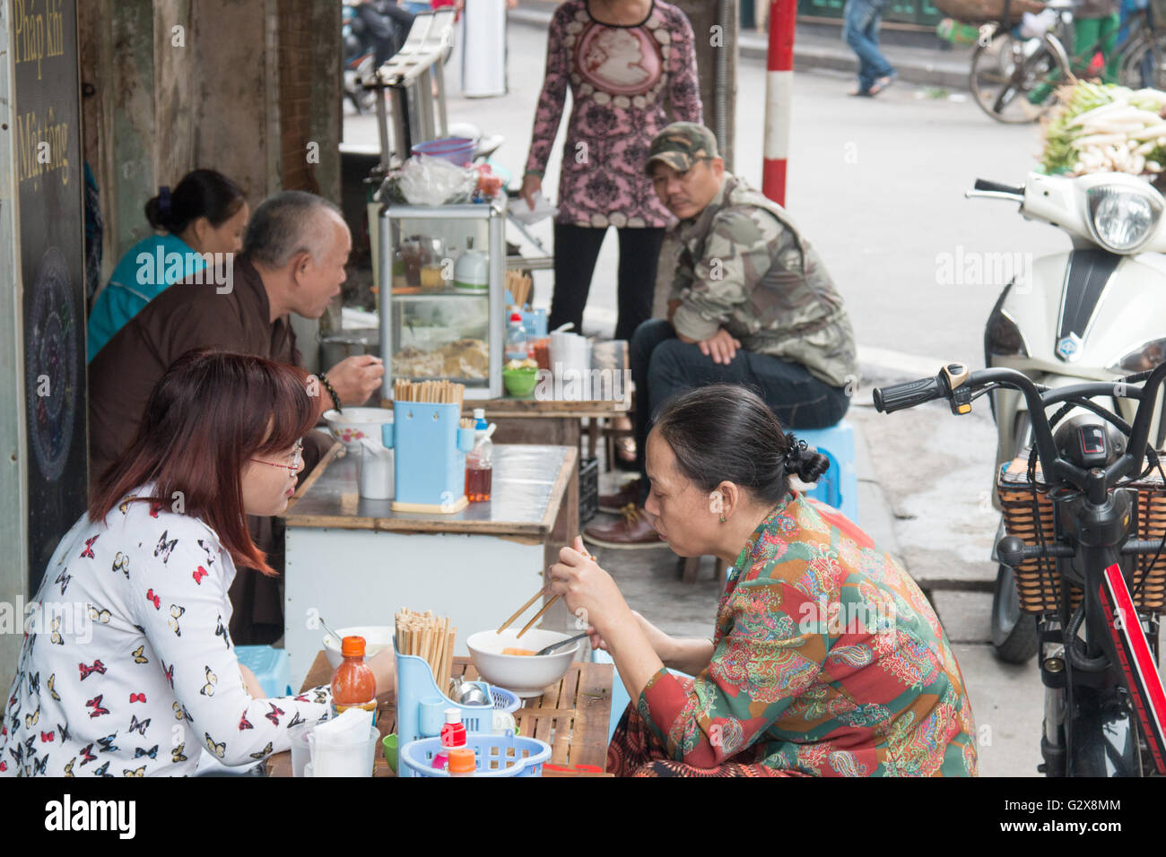 Local vietnamese people eating breakfast at a street cafe in Hanoi old ...
