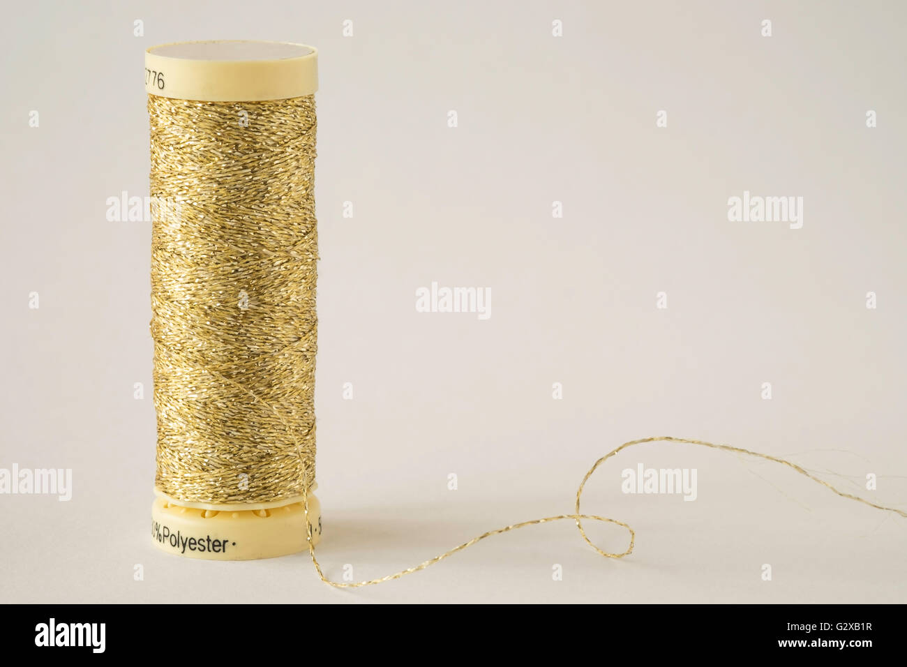Spool of shiny gold thread isolated on a white background with copy ...