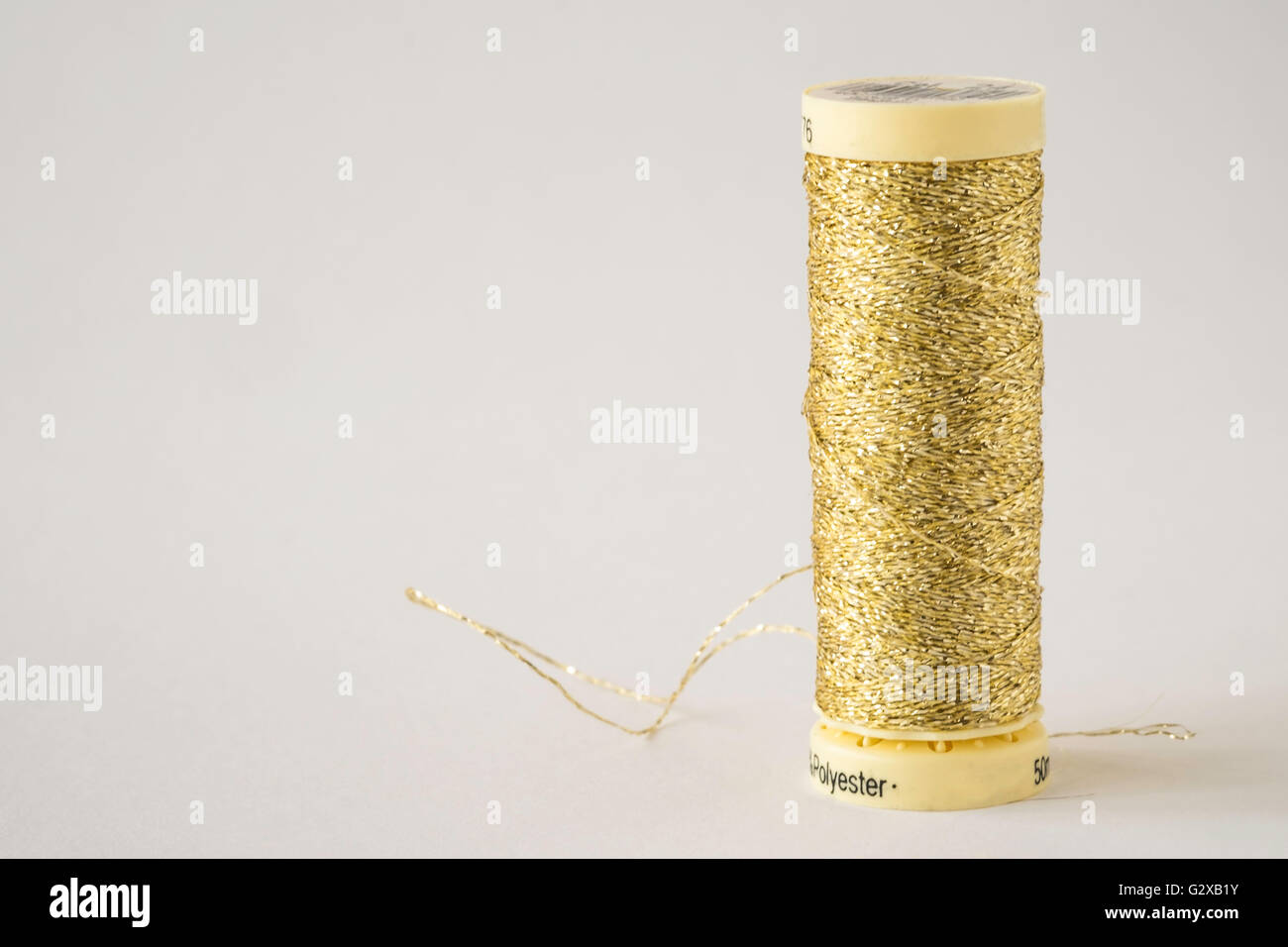 Spool of shiny gold thread isolated on a white background with copy ...