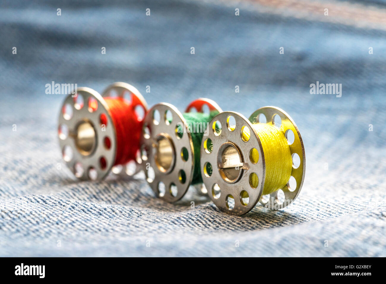 Rolls of sewing tread and blue jeans background with natural lighting ...