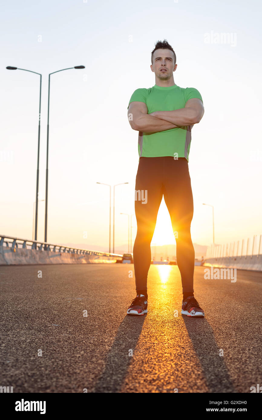 Portrait of male runner taking break after run while standing on a pier ...