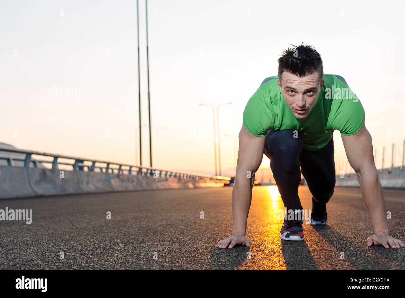 Portrait of a sports man in start position outdoors. Reading for run ...