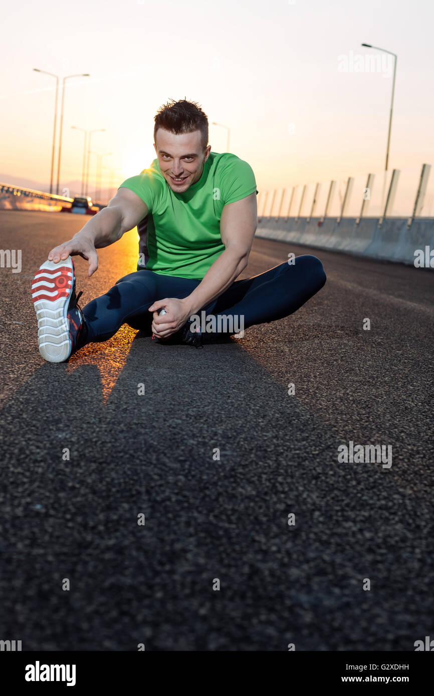 Stretching after jogging. sunset shot on highway Stock Photo - Alamy