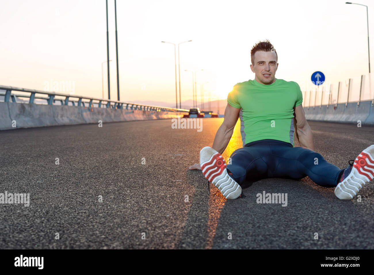 runner resting lying on a black asphalt after running. Jogging man ...