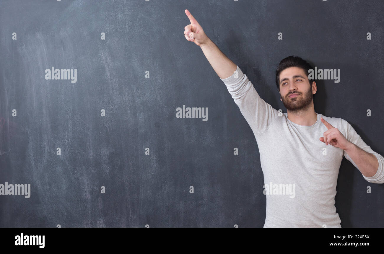 Handsome man with beard showing something on chalkboard, copy space ...
