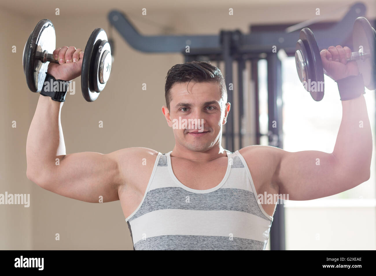 Athlete muscular bodybuilder man demonstrates his muscles in the gym ...