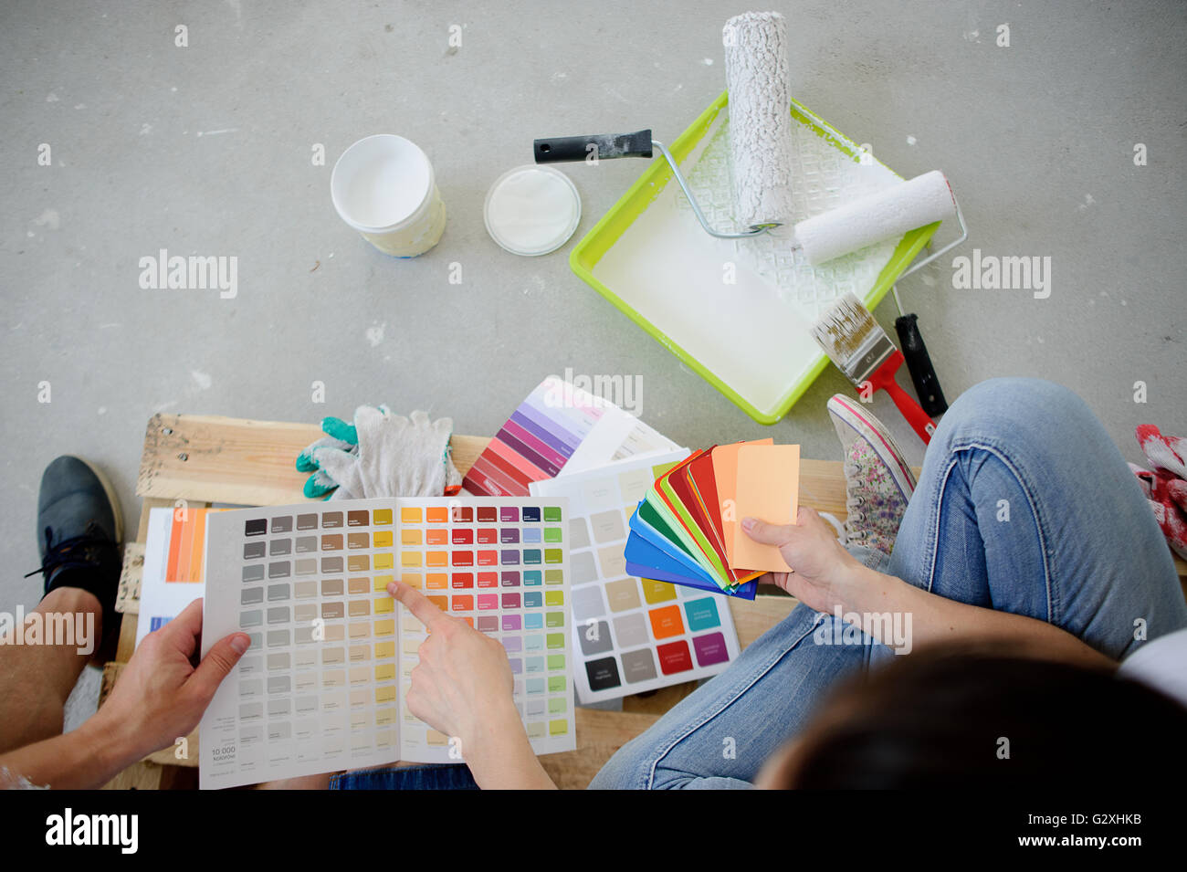 Two persons choose color of decor, sitting on a cement floor. Objects ...