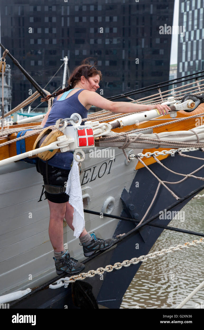 Female member of crew adjusting rigging on sailing ship. Crowds ...