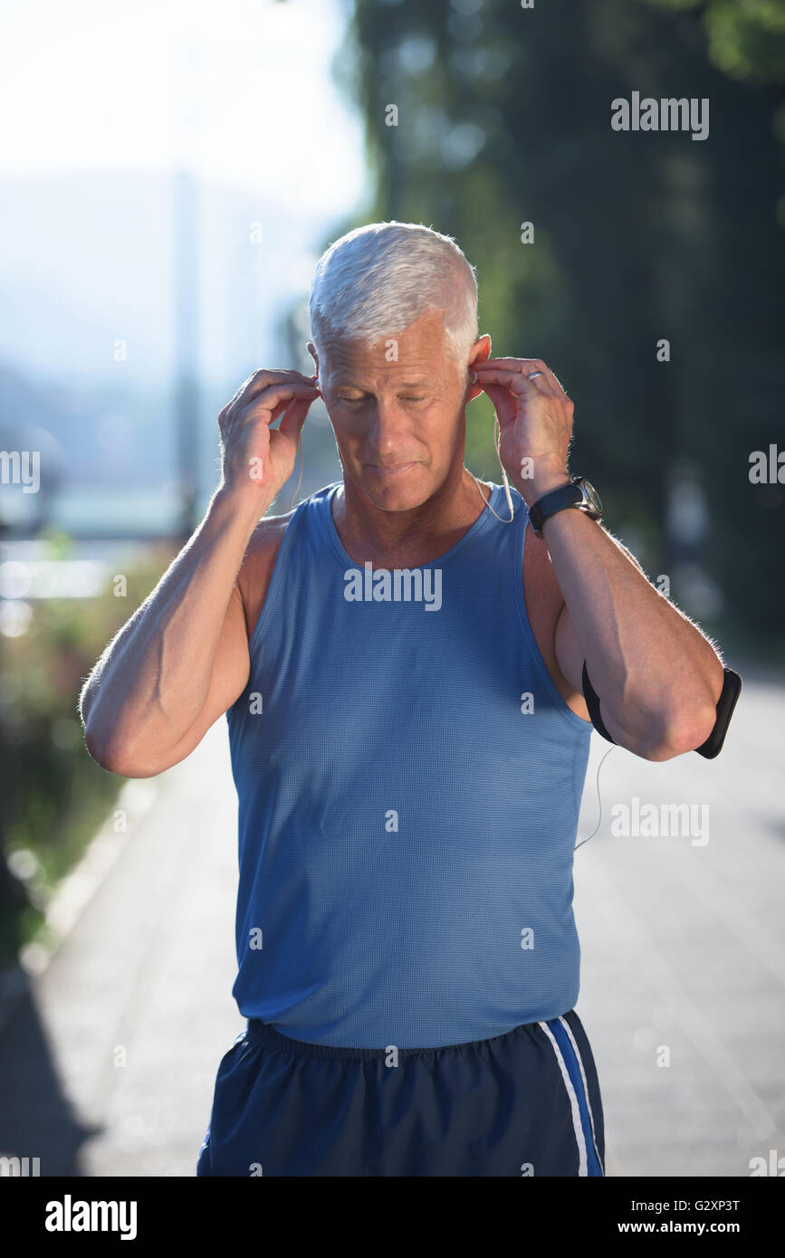 portrait of handsome senior jogging man while relaxing and take break ...