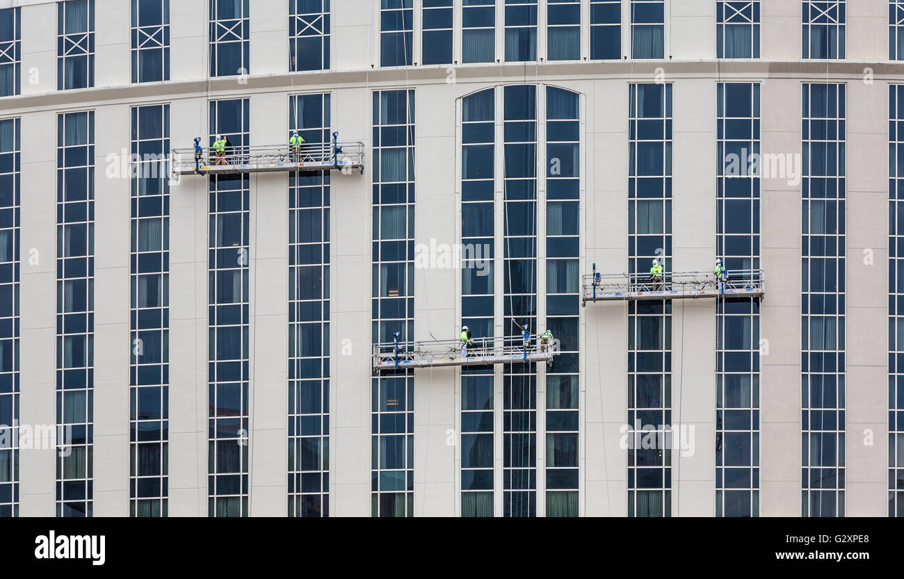 Window washers on electric scaffolding cleaning windows on high rise ...