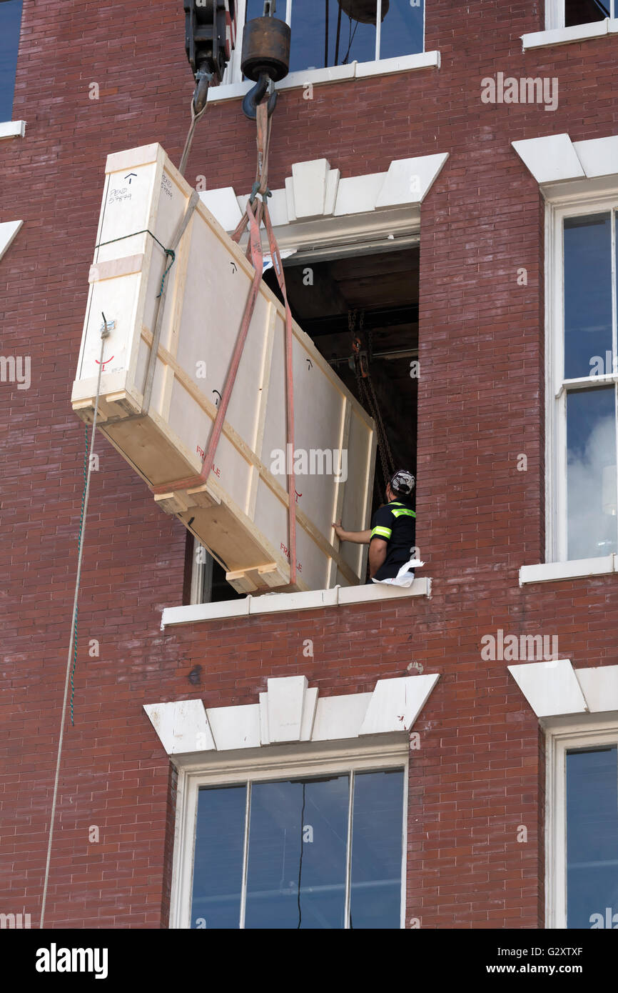 Delivery of a large wooden crate to an upper floor in a brick building ...