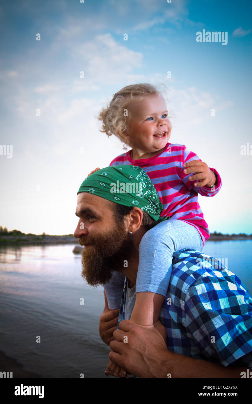 Dad or father and his baby daughter hugging on a boat or ferry in the sea on a cool summer day ...