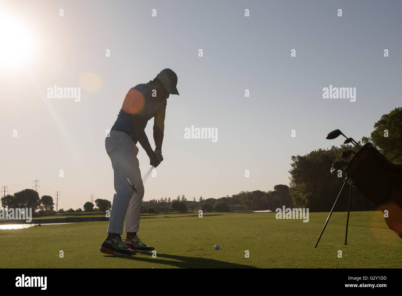 golf player hitting shot with club on course at beautiful morning with ...