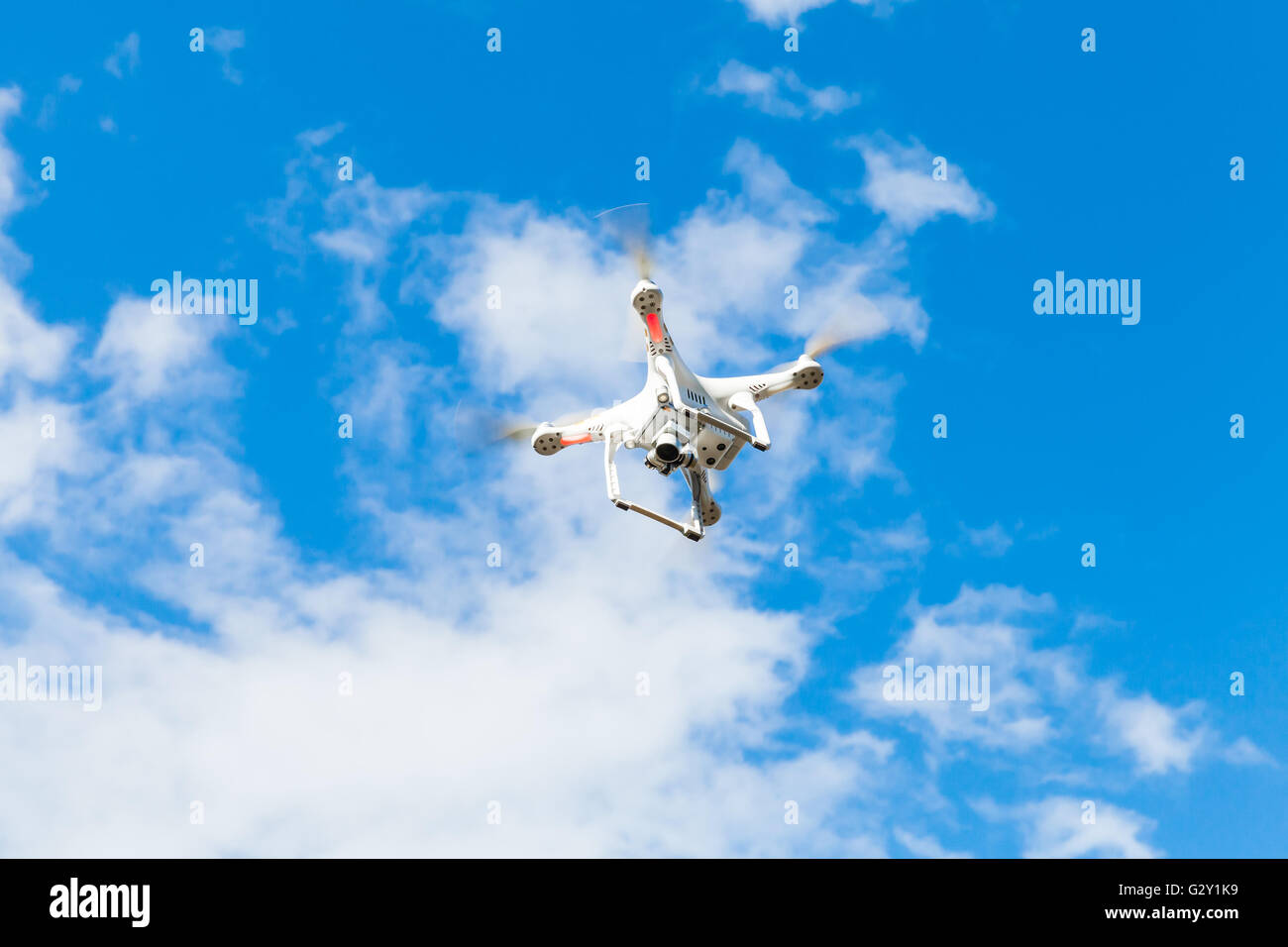 White quadrocopter flying in blue cloudy sky, drone controlled by ...