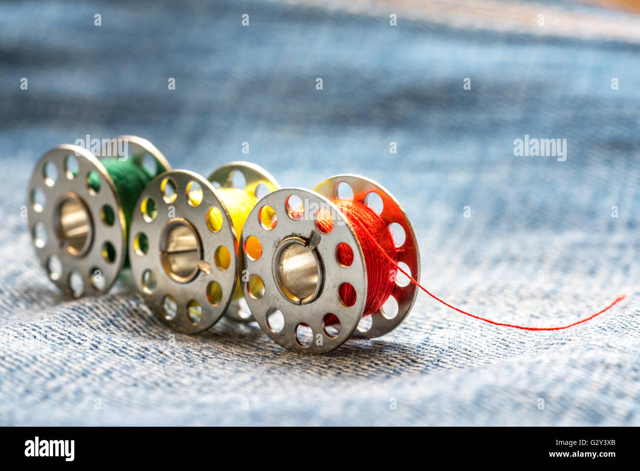 Rolls of sewing tread and blue jeans background with natural lighting ...