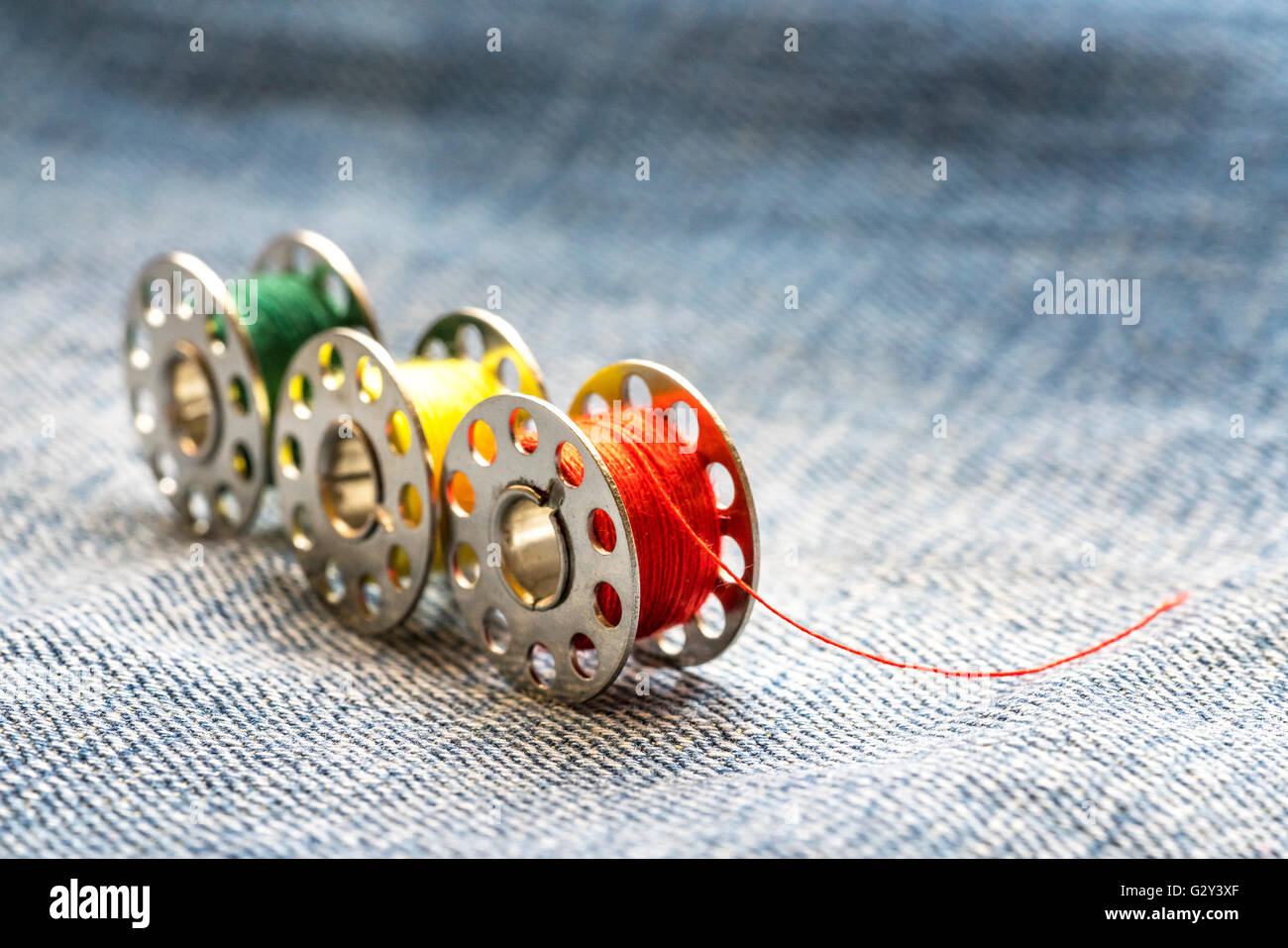Rolls of sewing tread and blue jeans background with natural lighting ...