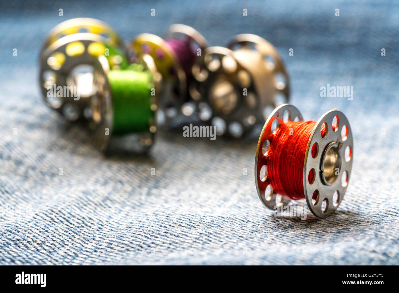Rolls of sewing tread and blue jeans background with natural lighting ...