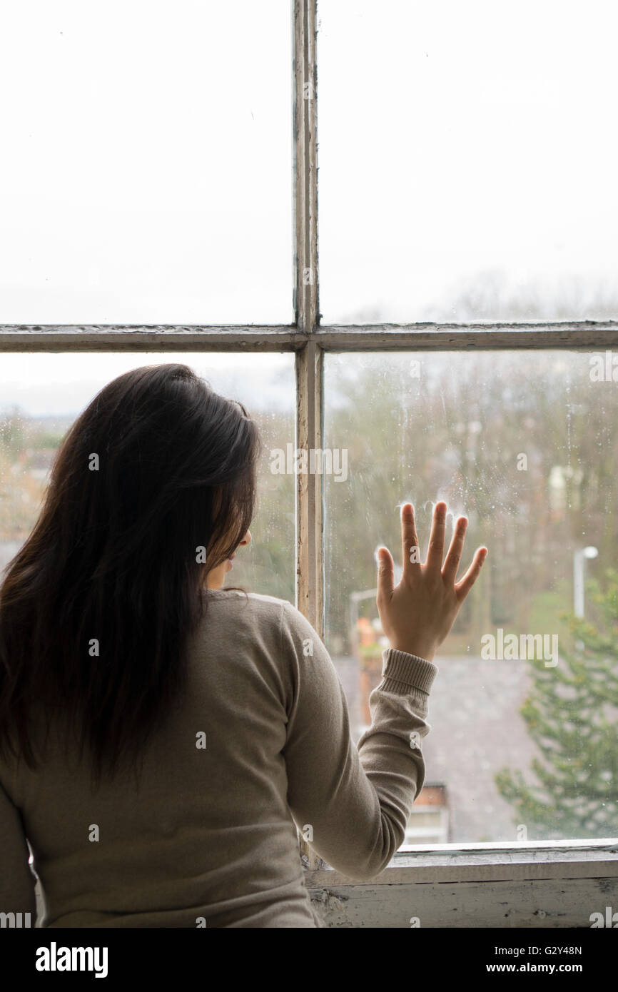Rear view of a woman standing by the window Stock Photo - Alamy