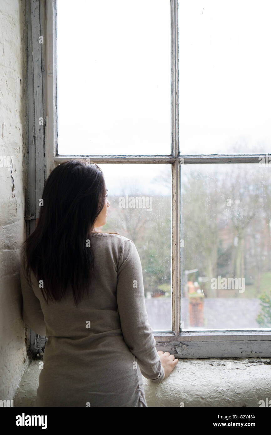 Rear view of a woman standing by the window Stock Photo - Alamy