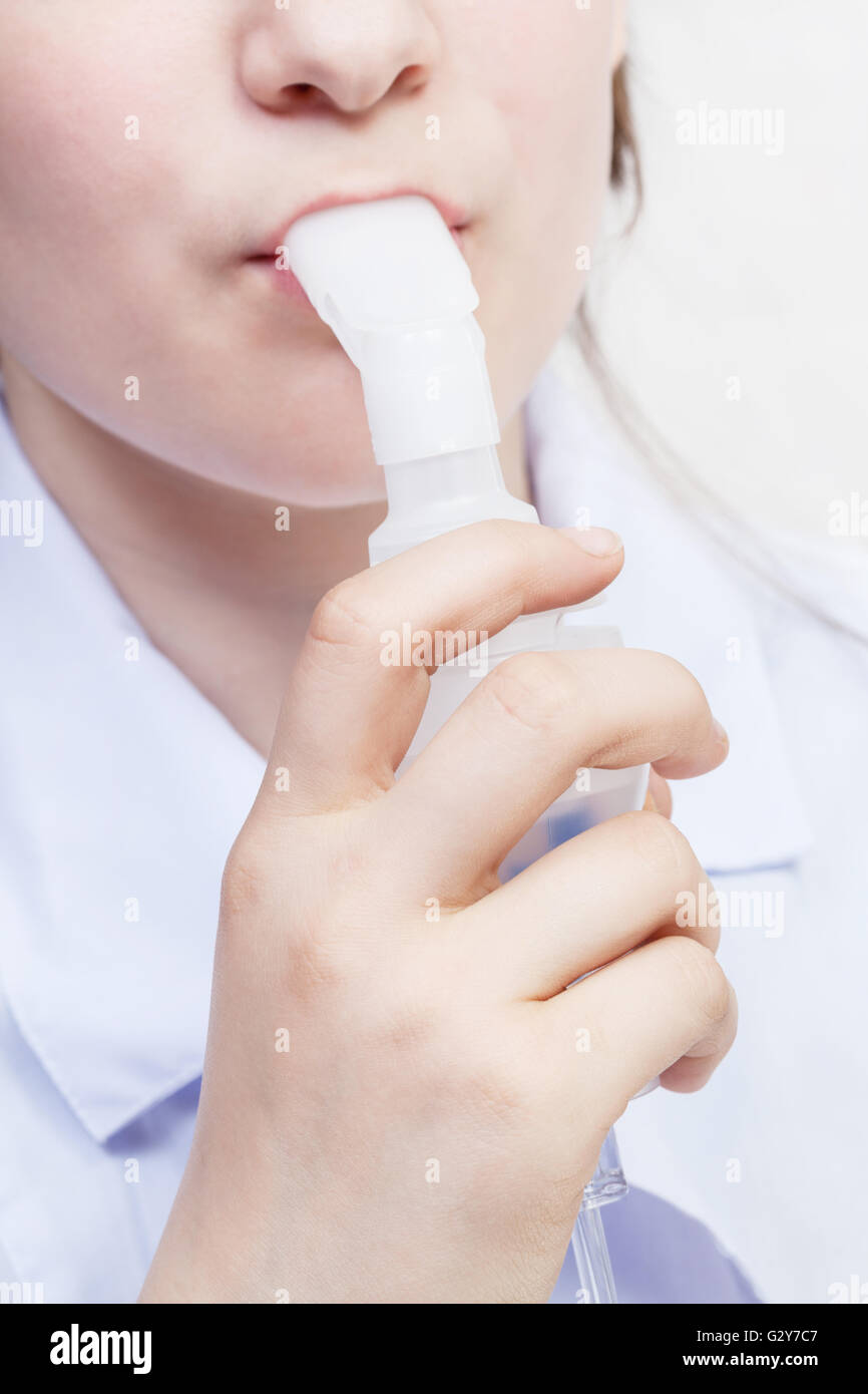 medical inhalation treatment - girl inhales with mouthpiece of modern ...