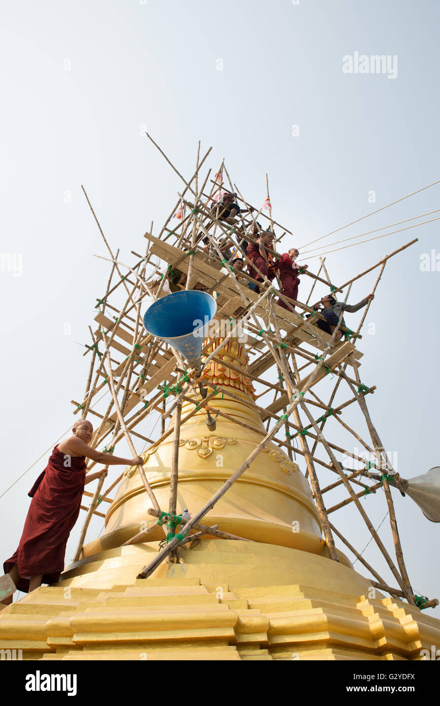 Preparing to mount the golden umbrella on the top of the stupa during ...