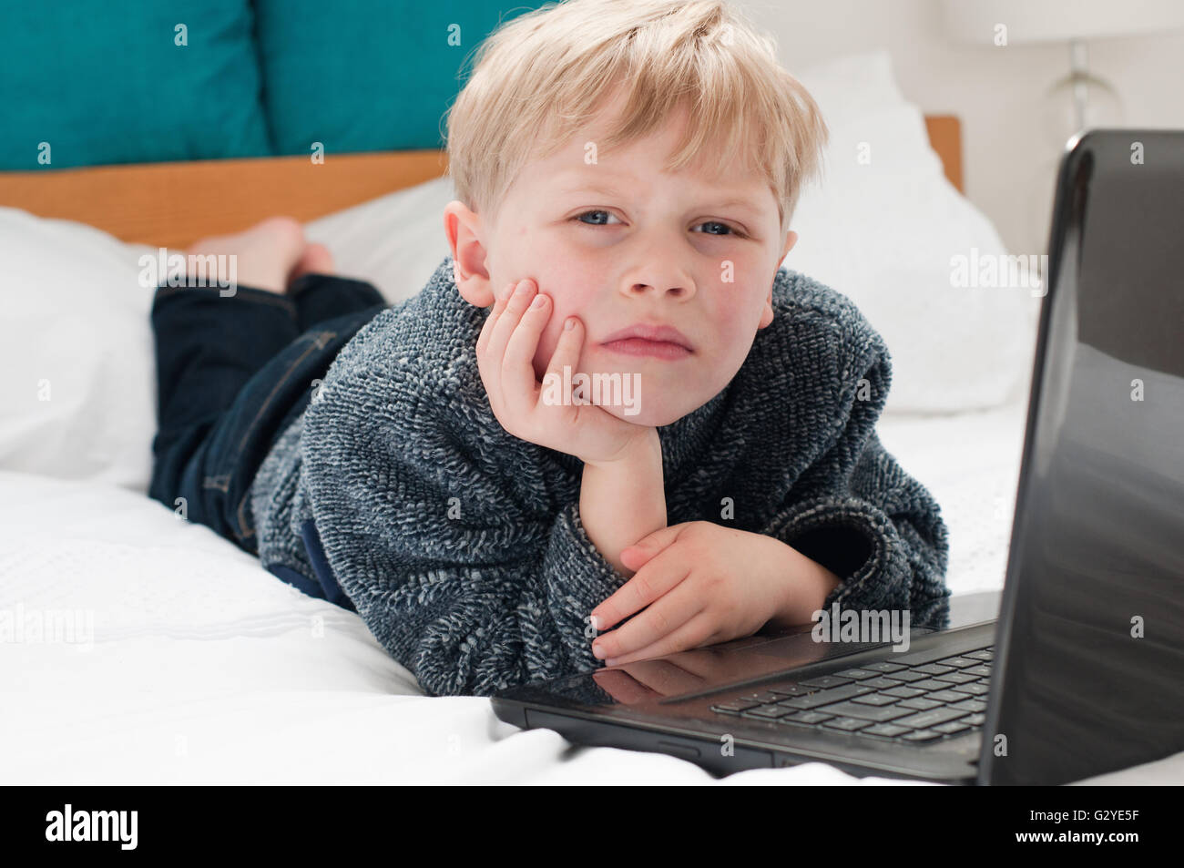 Child on bed using a laptop Stock Photo - Alamy