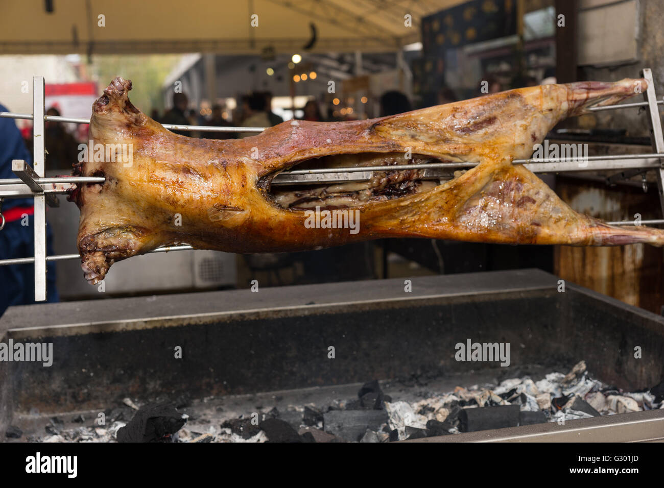 Whole lamb or pig roasting on a spit over a bed of hot charcoal at an ...
