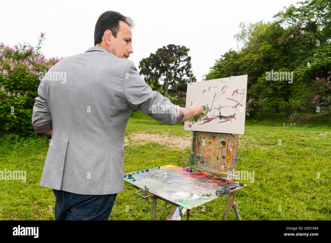 Male artist looking through a park during creation a sketch of his ...