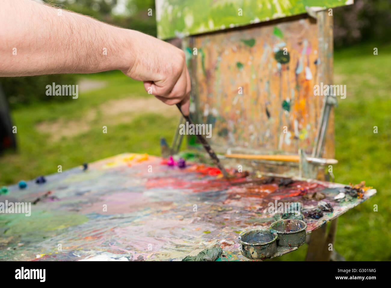 Male hand mixing dark colors of oils and acrylics paint with a ...